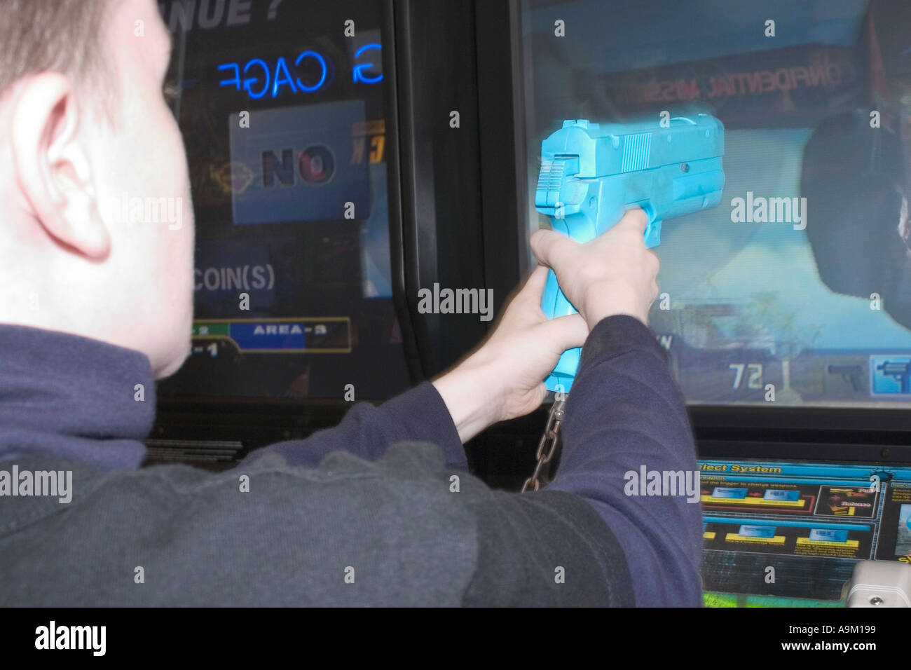 Boy playing video game with toy gun in arcade Stock Photo - Alamy