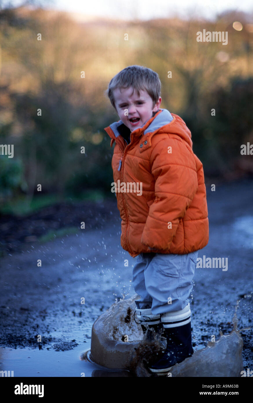 young boy jumping in muddy puddle in wet winter Stock Photo - Alamy