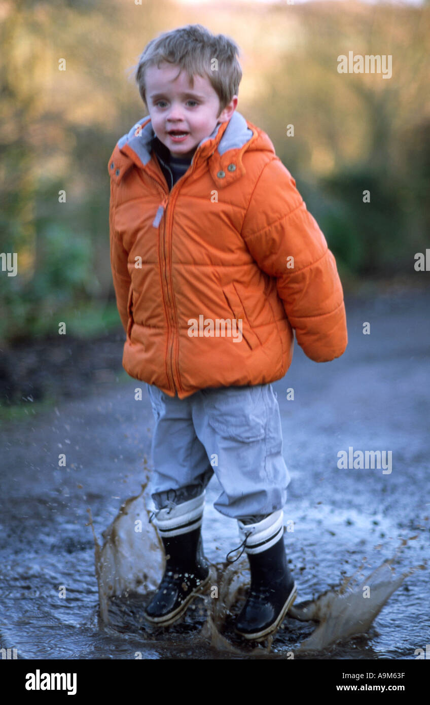 young child jumping in muddy puddle splashing in the winter Stock Photo ...