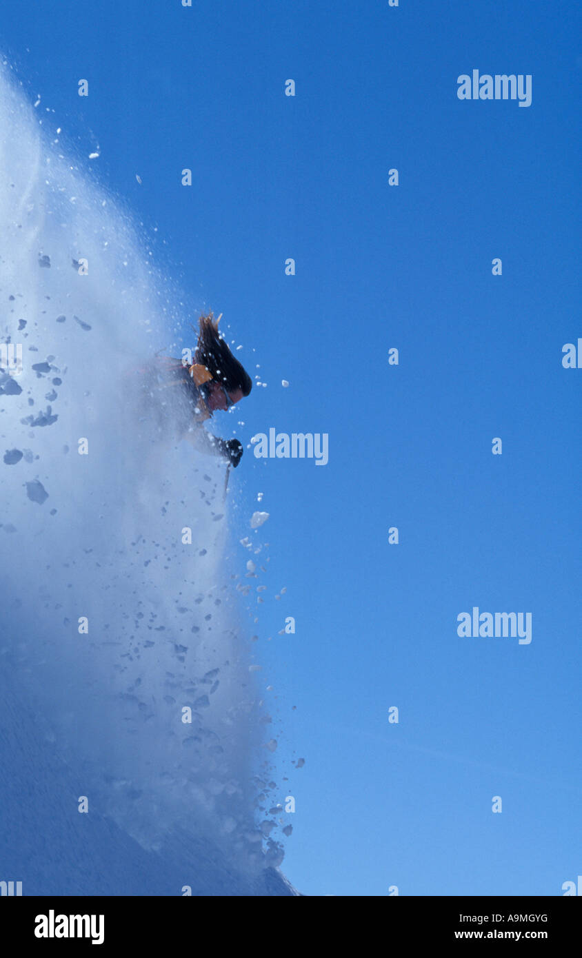 Dramatic image of extreme female skier in clouds of snow coming down a ...