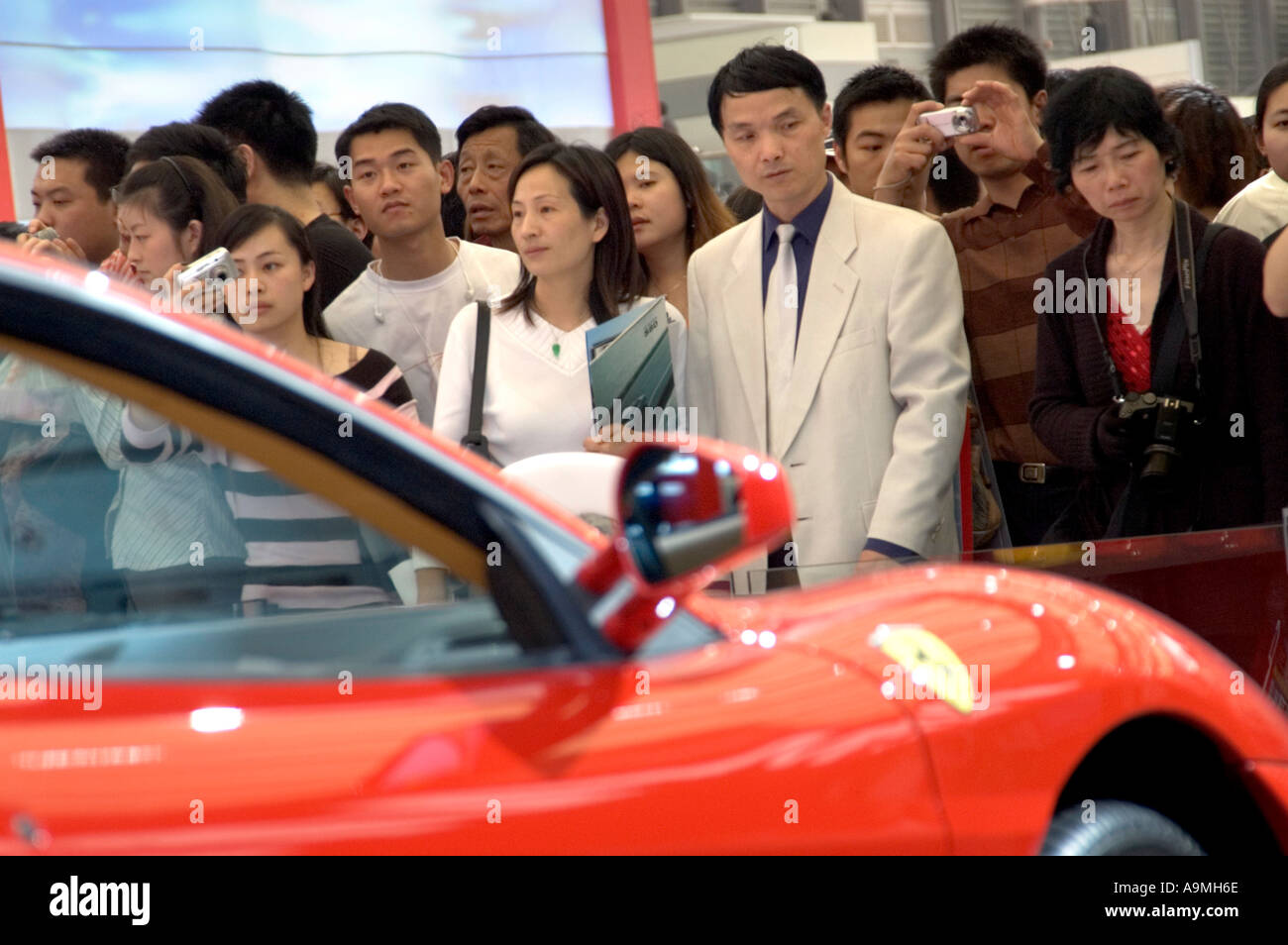 PEOPLE LOOKING AT A RED FERRARI SPORTS CAR DURING THE SHANGHAI AUTO ...