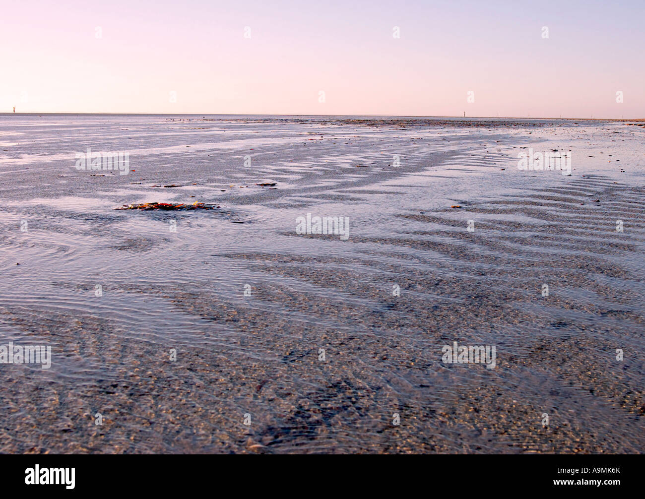 the sky and shallow water on a tropical beach turn pink as the sun goes ...