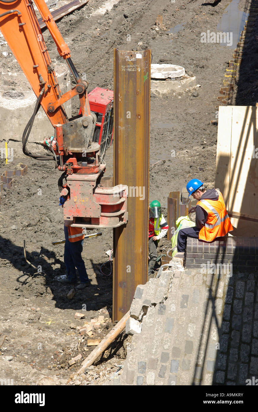 Hydraulic sheet steel pile driver attached to excavator arm placing ...