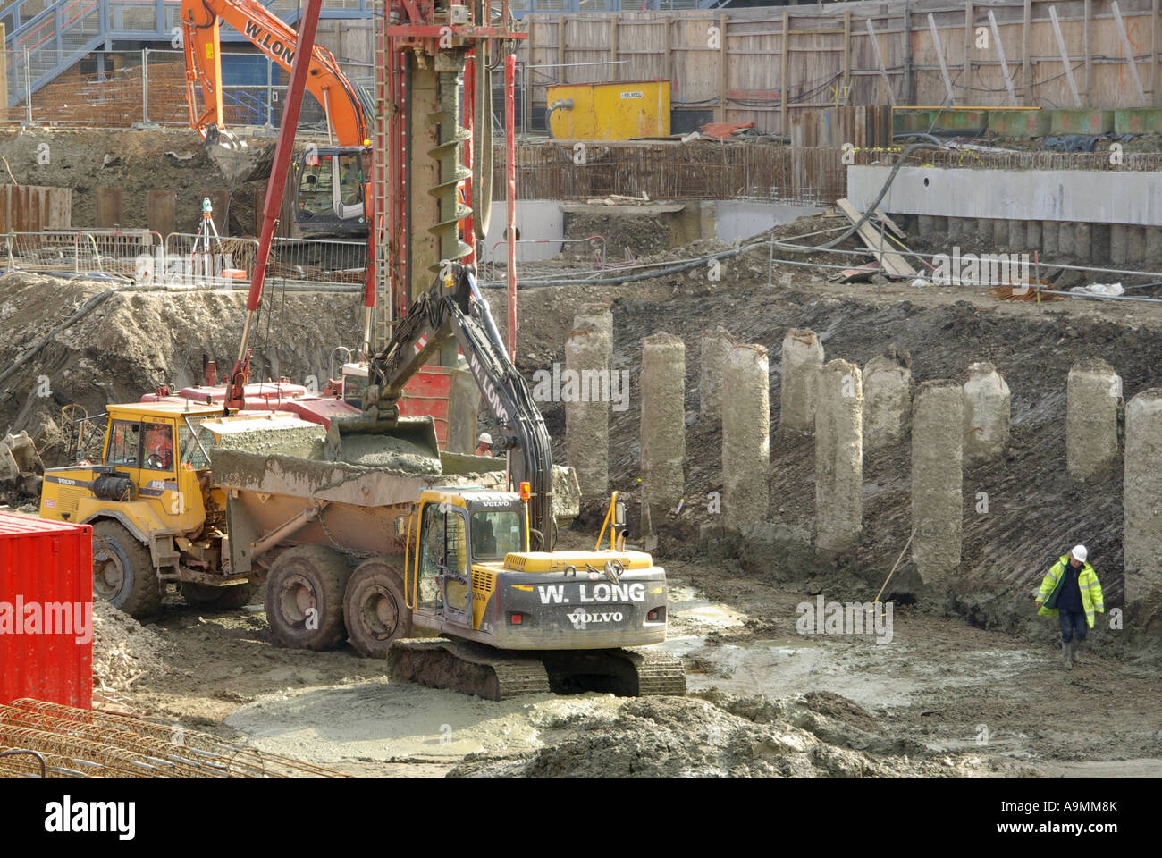 Construction site mechanical excavator working alongside pile boring ...
