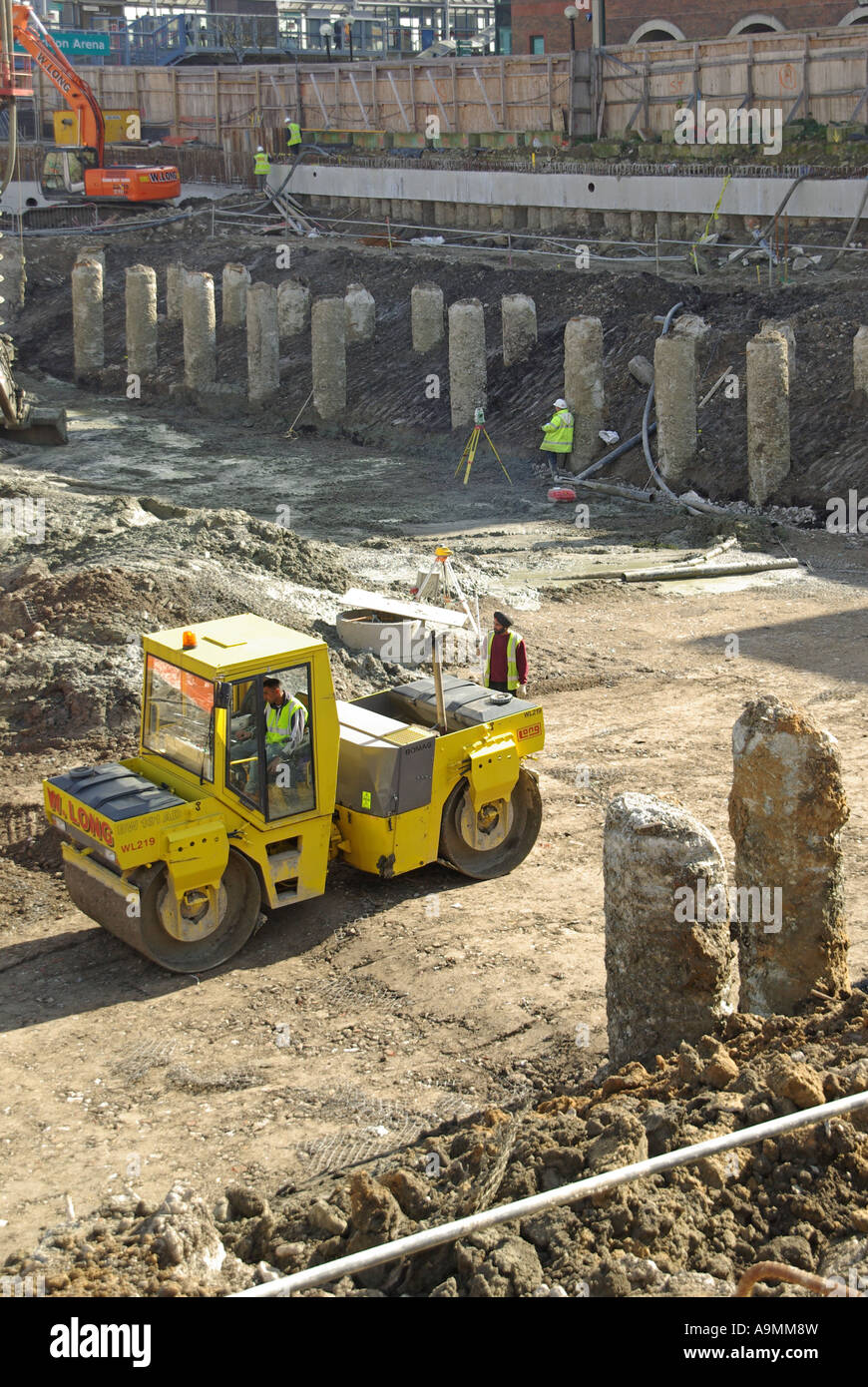 Construction site heavy vibrating roller compacts fill to basement ...