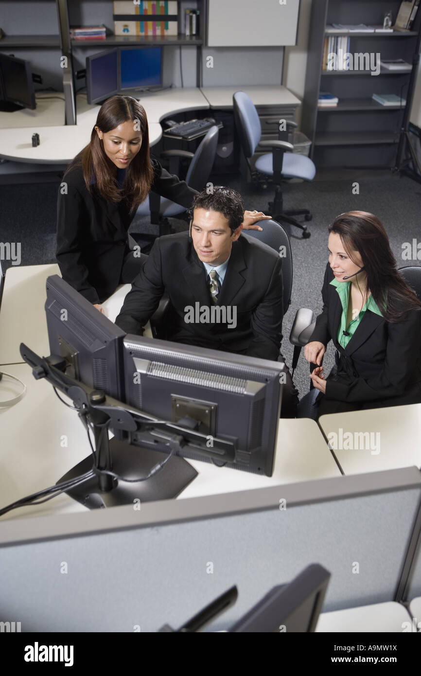 Co-workers working together at a desk looking at computer screens Stock ...