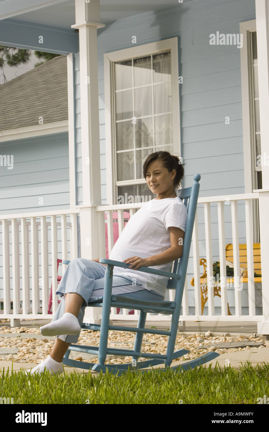 Pregnant woman sitting on a rocking chair in front of house Stock Photo ...