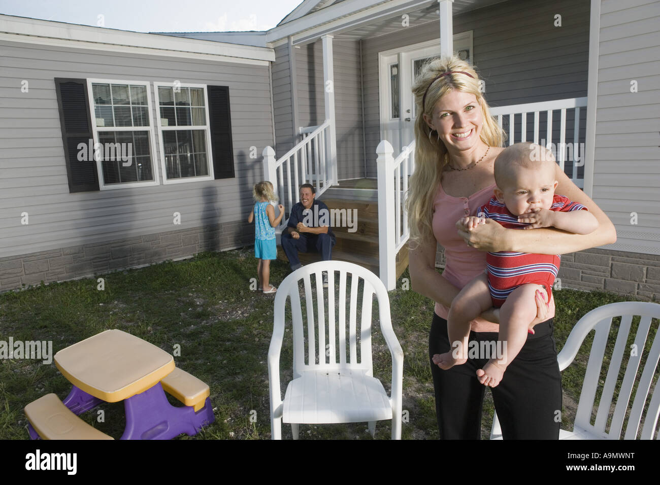 Portrait of a woman holding a baby in front of a trailer home Stock ...