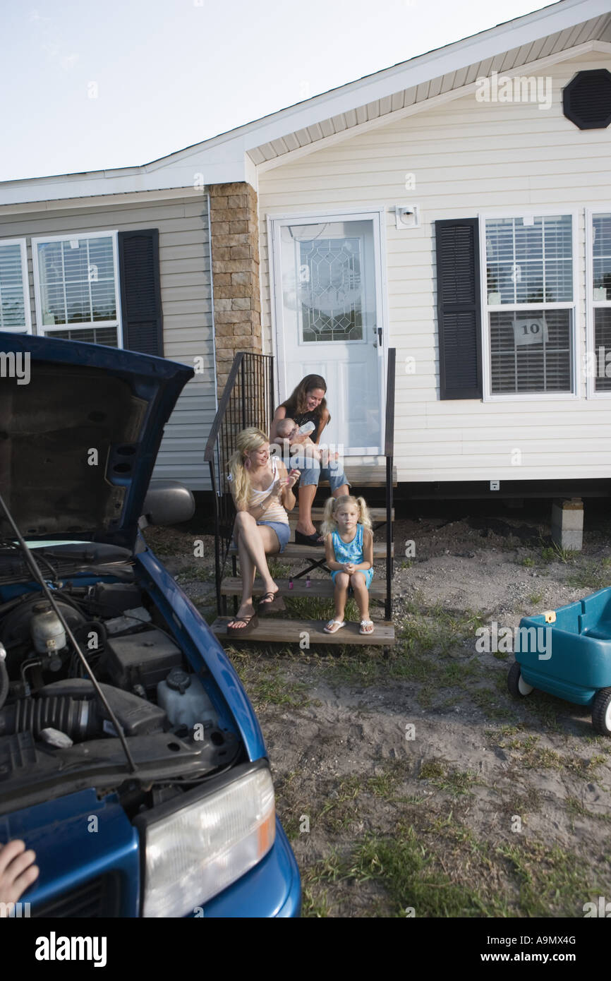 Young women and children sitting on front steps of trailer home Stock ...