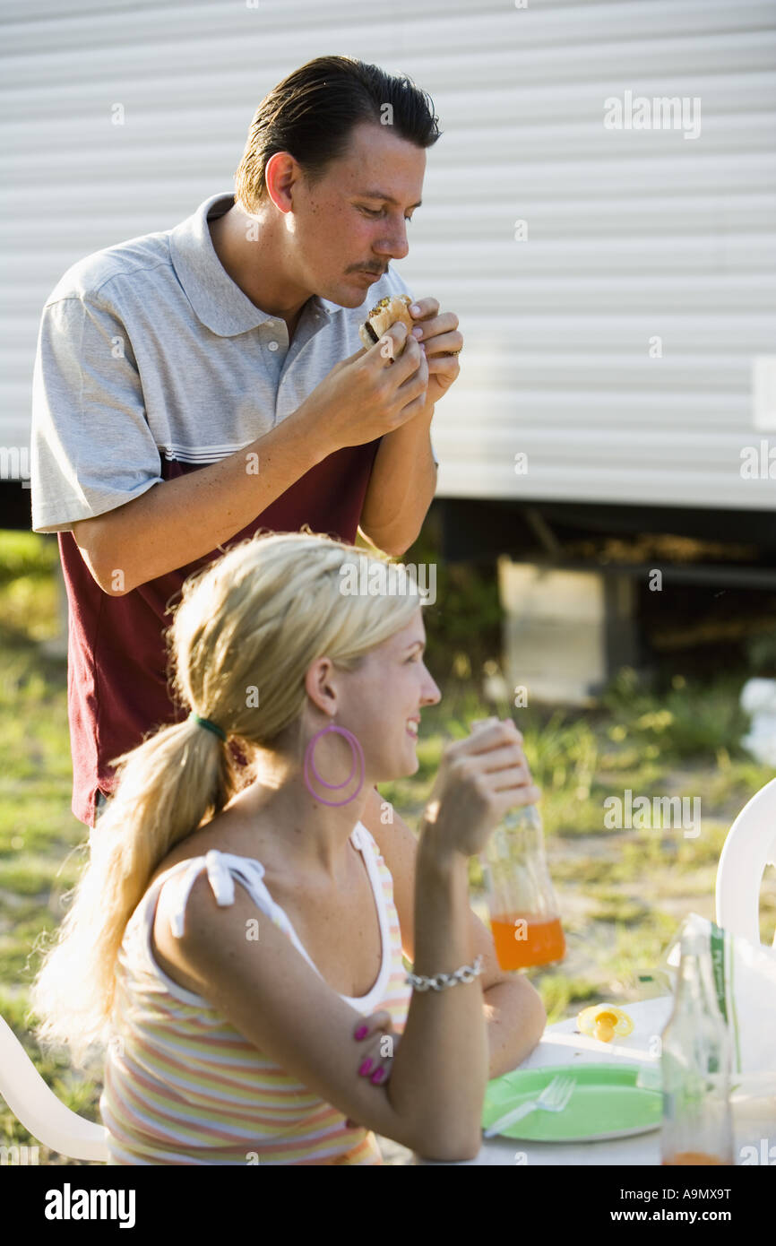 View of a happy couple eating and drinking at a cookout in front of a ...