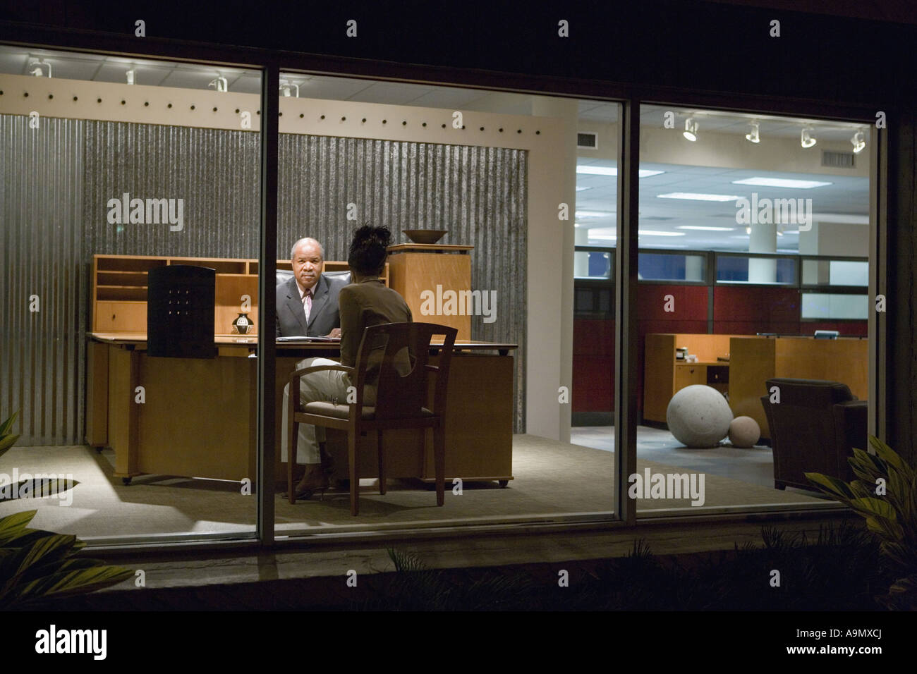 View through window of man and woman talking in an office Stock Photo ...