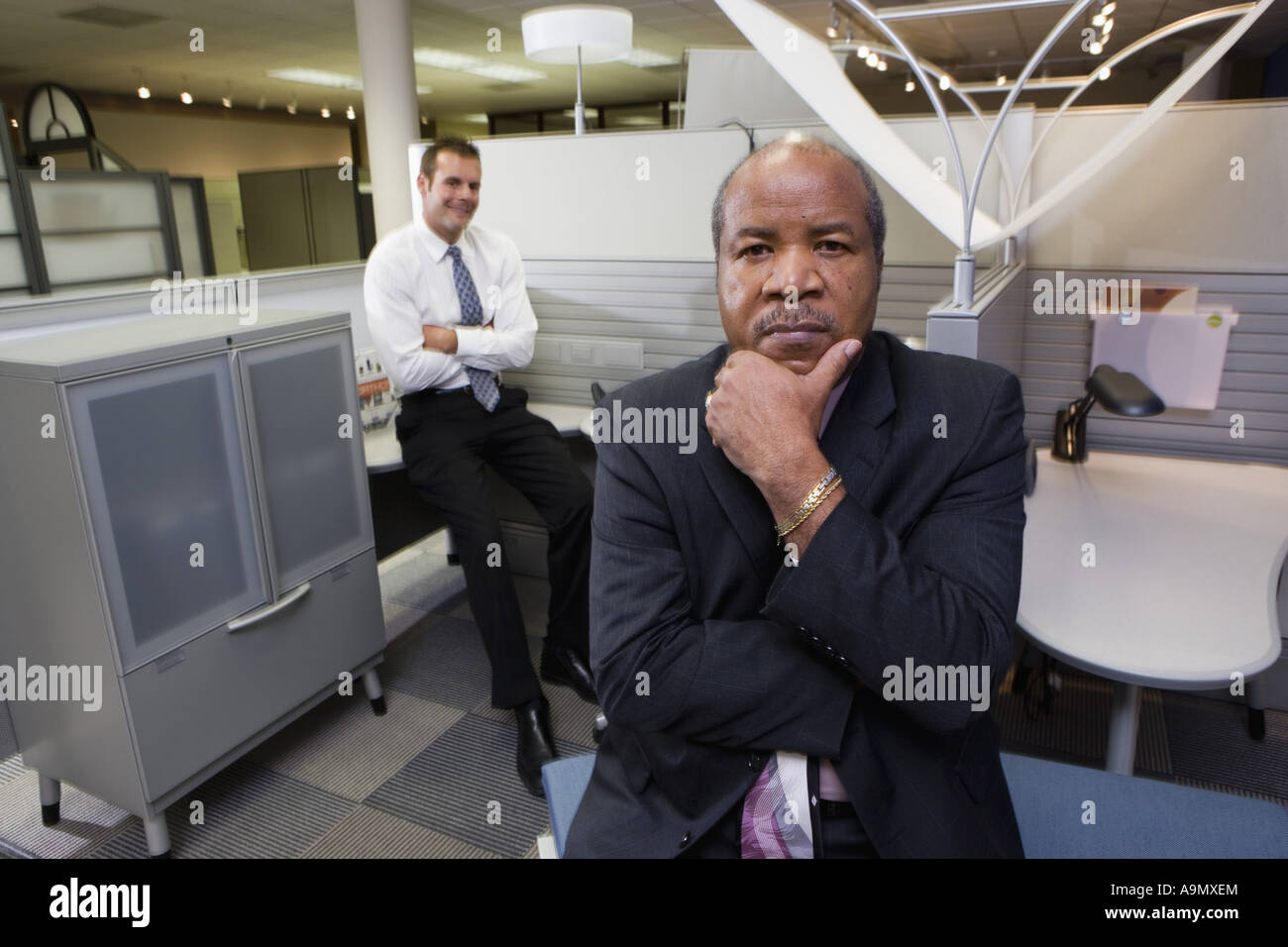 Portrait of a serious manager thinking while younger office worker ...