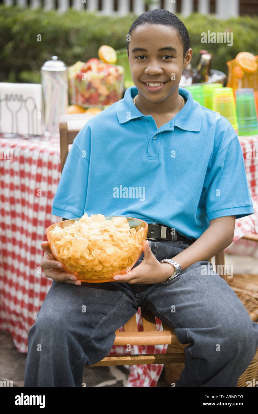Portrait of a seated teenage boy holding a bowl of snacks Stock Photo ...