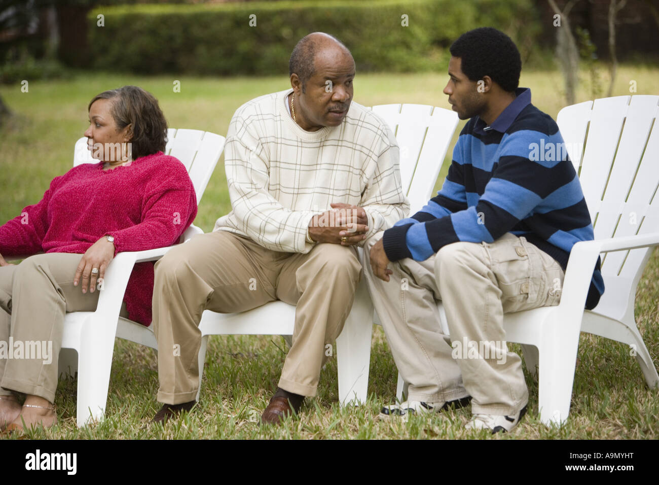 Father and son talking with mother in background Stock Photo - Alamy