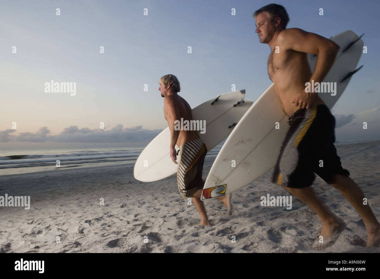 Surfer dudes running towards surf with surfboards Stock Photo - Alamy