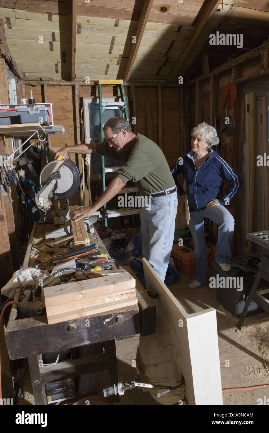Mature man working with tools while wife watches Stock Photo - Alamy