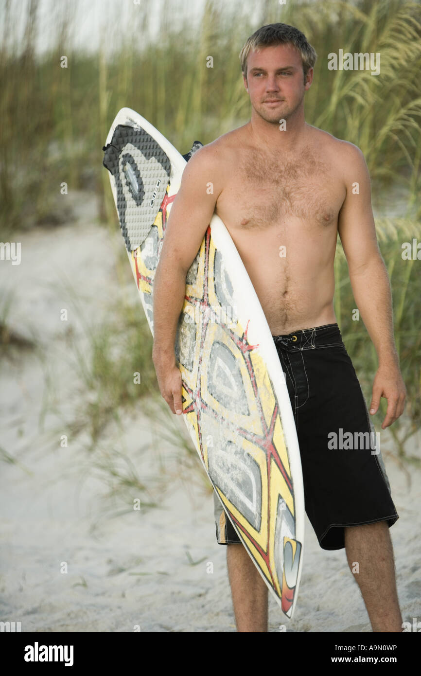 Surfer dude standing on beach with a surfboard Stock Photo - Alamy