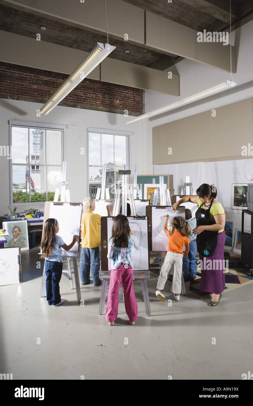 An art teacher with her students drawing on easels in art class Stock ...