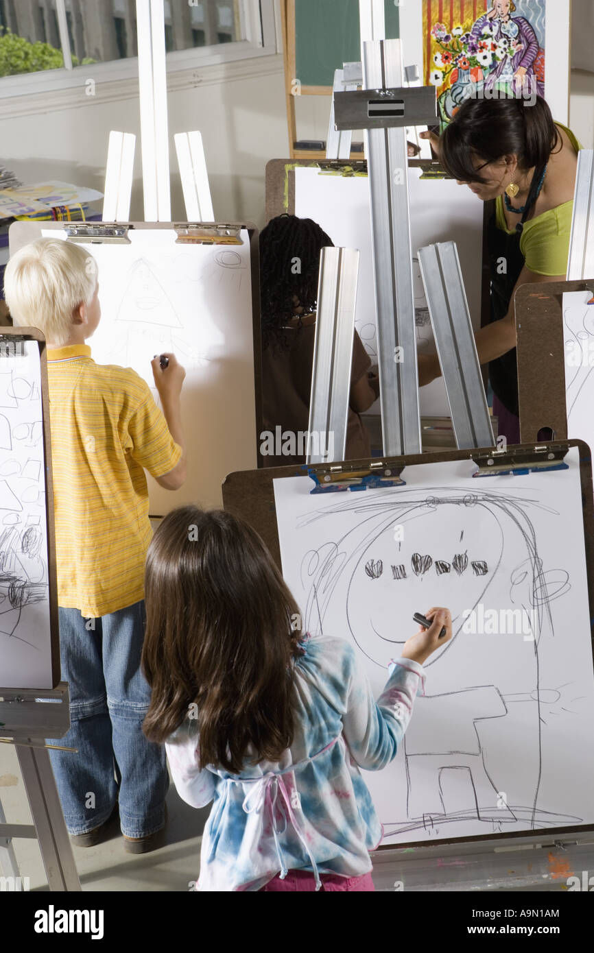 An art teacher with her students drawing on easels in art class Stock ...