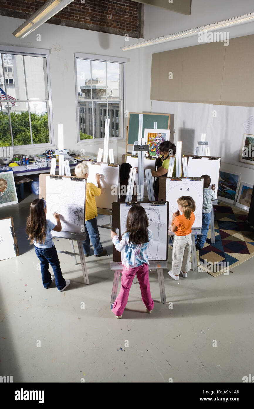An art teacher with her students drawing on easels in art class Stock Photo - Alamy
