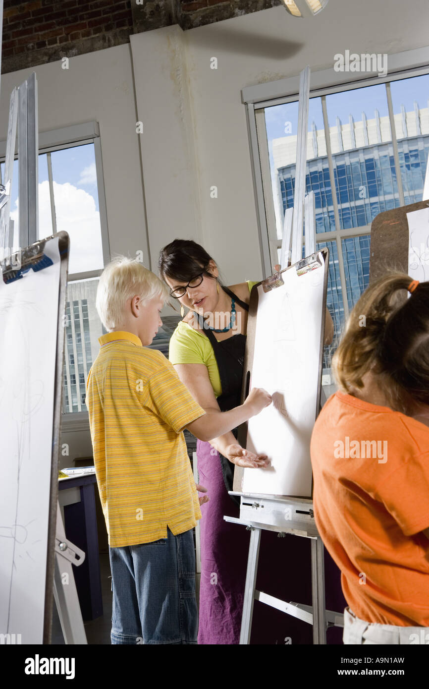 An art teacher with her students drawing on easels in art class Stock ...