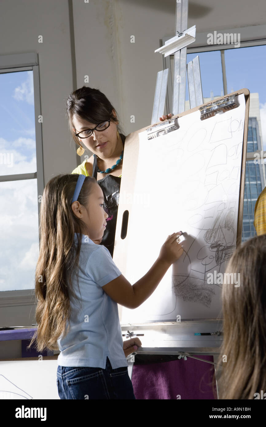An art teacher with her students drawing on easels in art class Stock ...