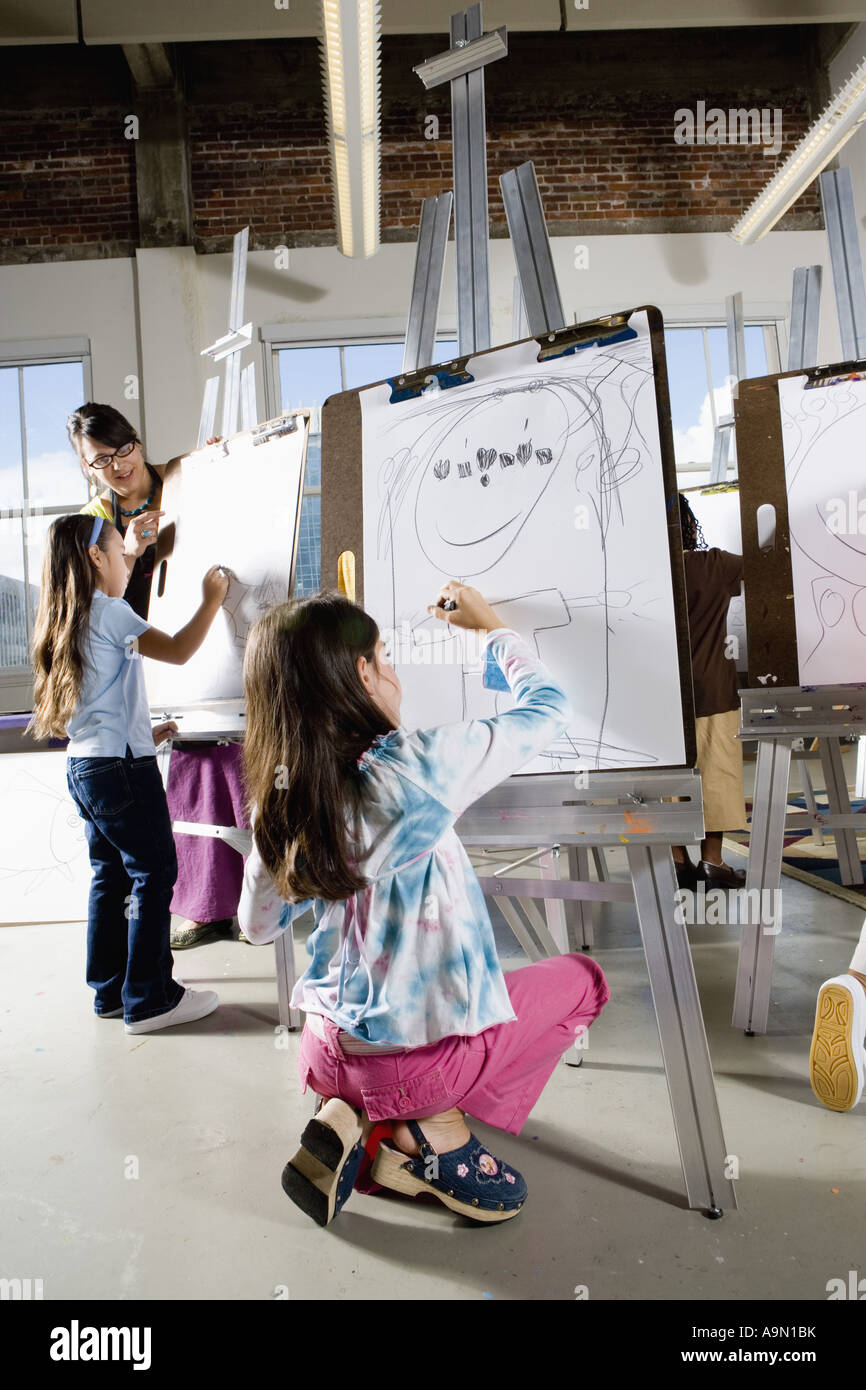 An art teacher with her students drawing on easels in art class Stock Photo - Alamy