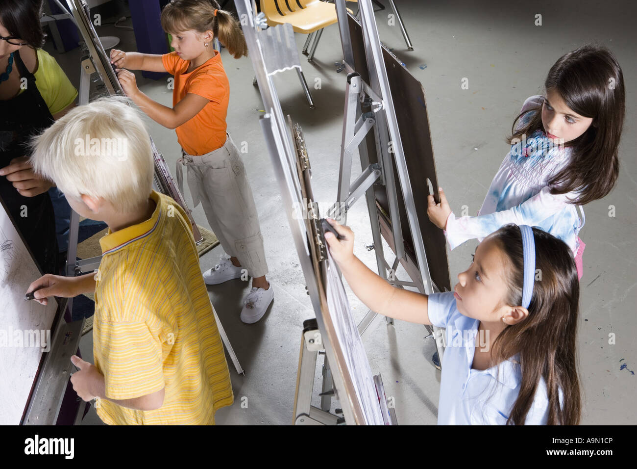 An art teacher with her student drawing on easels in art class Stock ...
