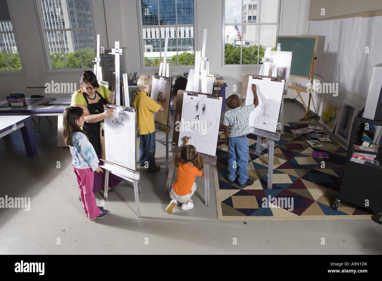An art teacher with her student drawing on easels in art class Stock ...