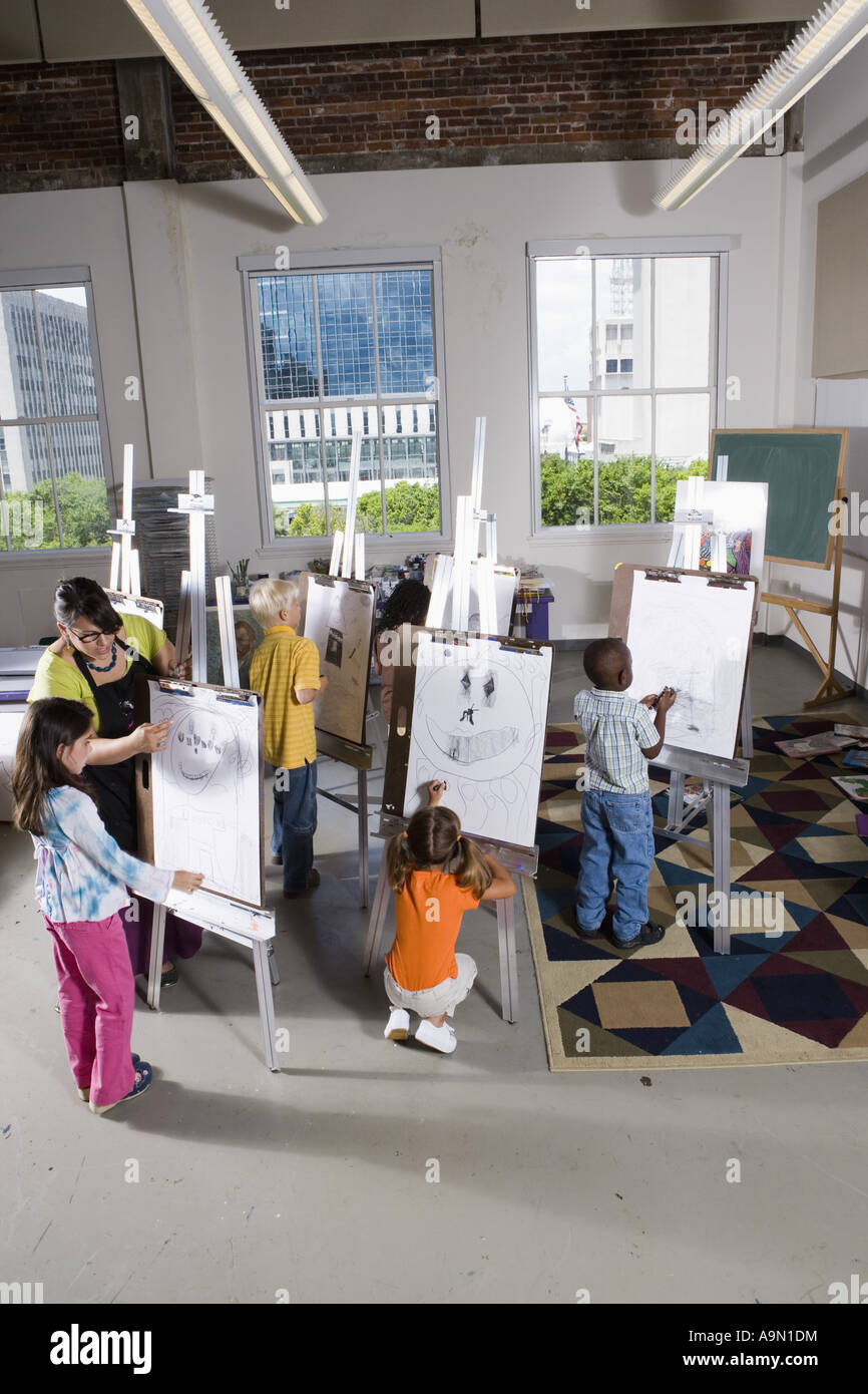 An art teacher with her student drawing on easels in art class Stock ...