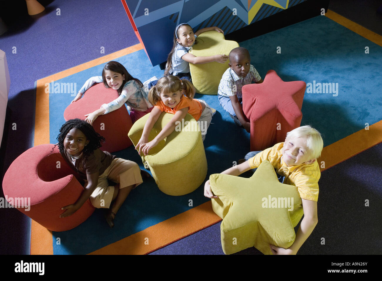 Elevated view of children hugging colorful seats of various shapes ...