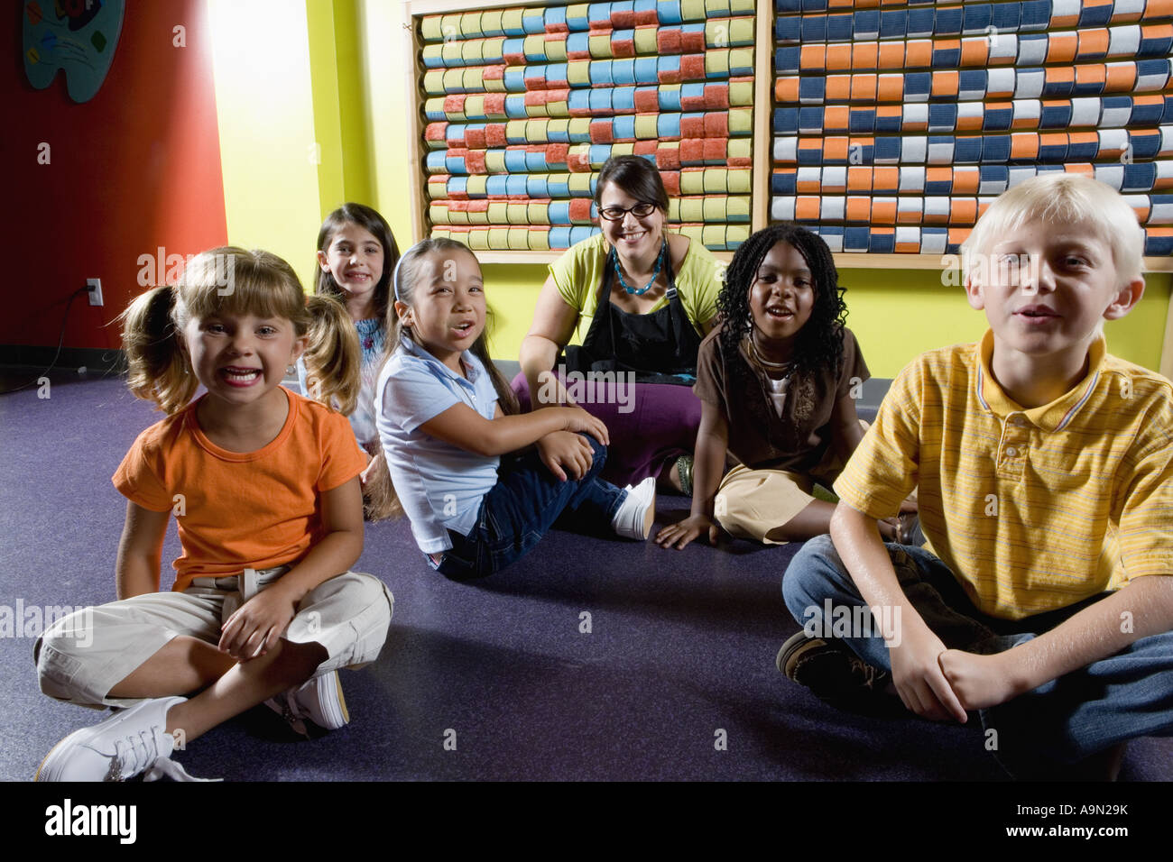 Teacher sitting with young children Stock Photo - Alamy
