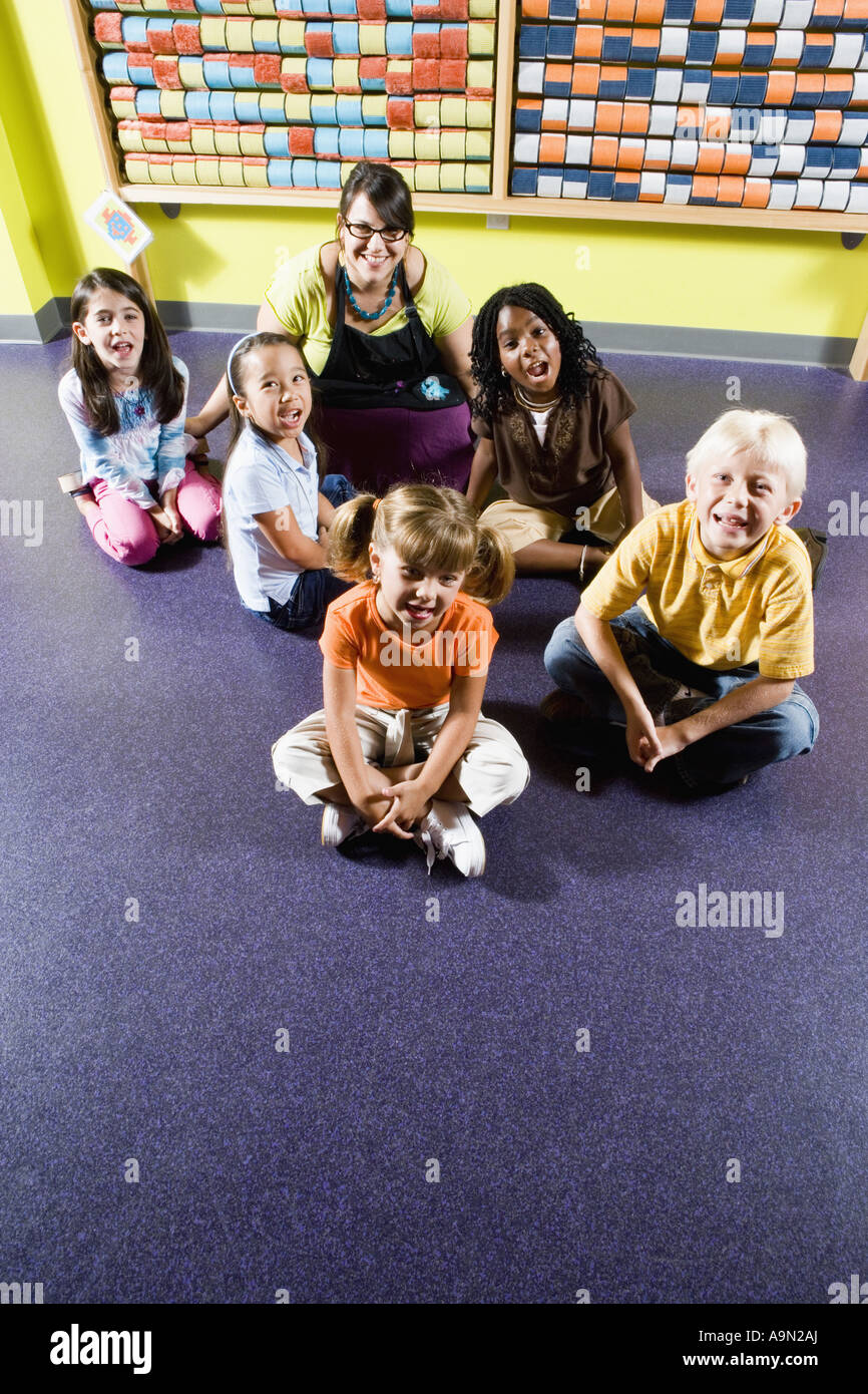 Teacher sitting with young children Stock Photo - Alamy
