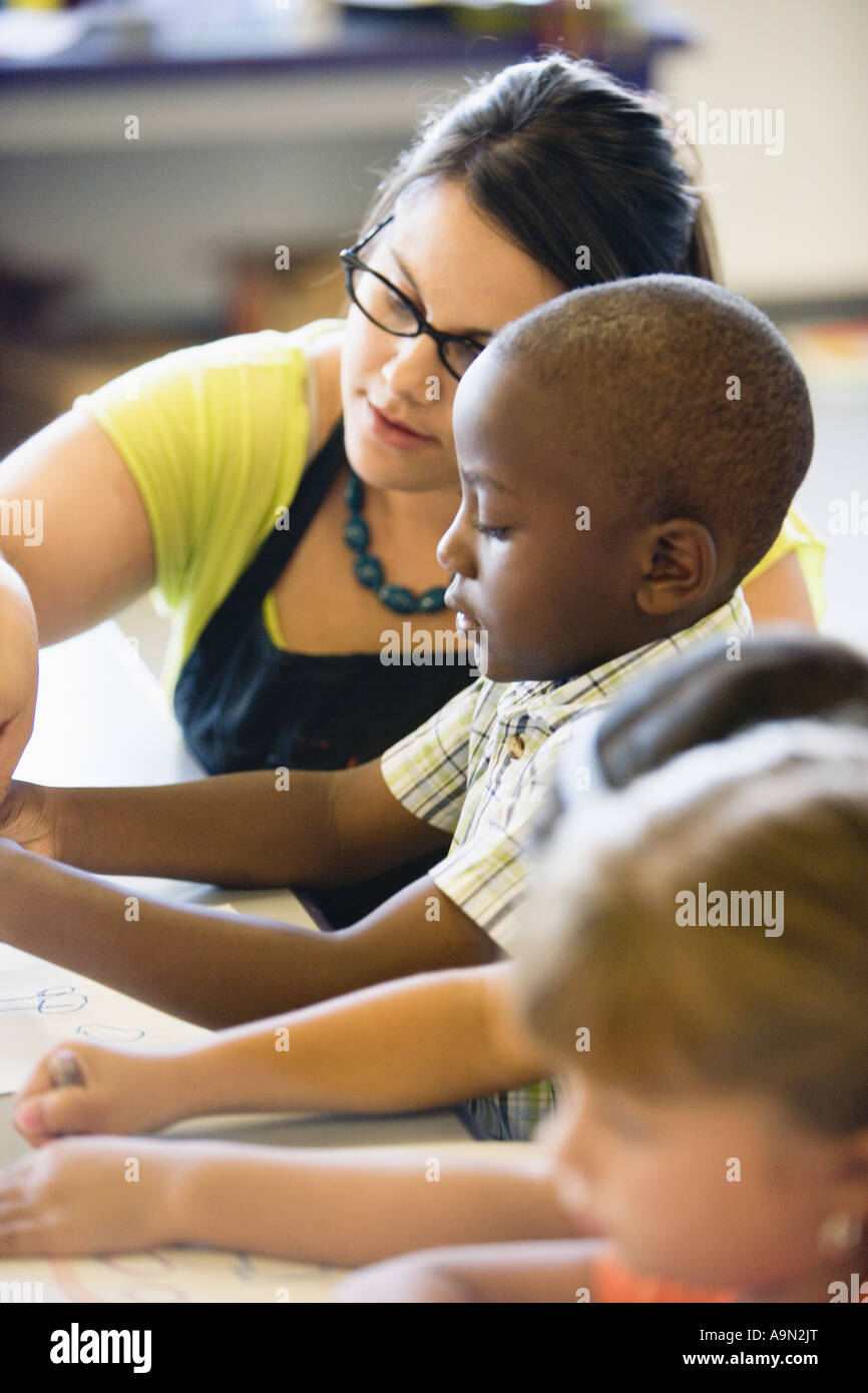 Close up of teacher helping young children in class Stock Photo - Alamy