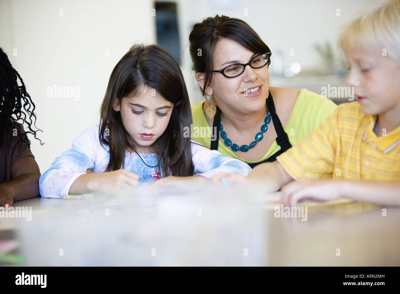 Close up of teacher helping young children in class Stock Photo - Alamy