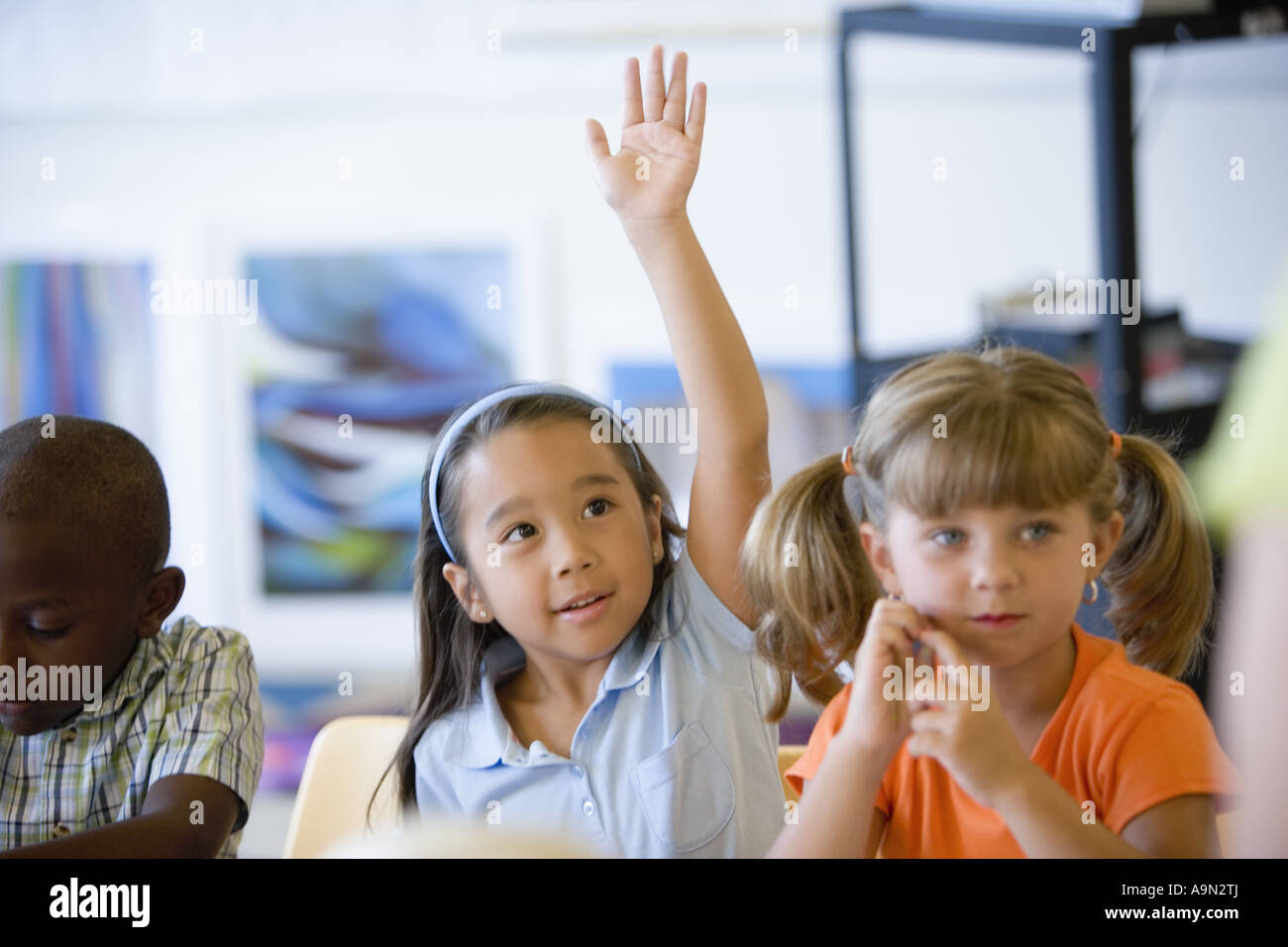 Little girl raising her hand in class Stock Photo - Alamy