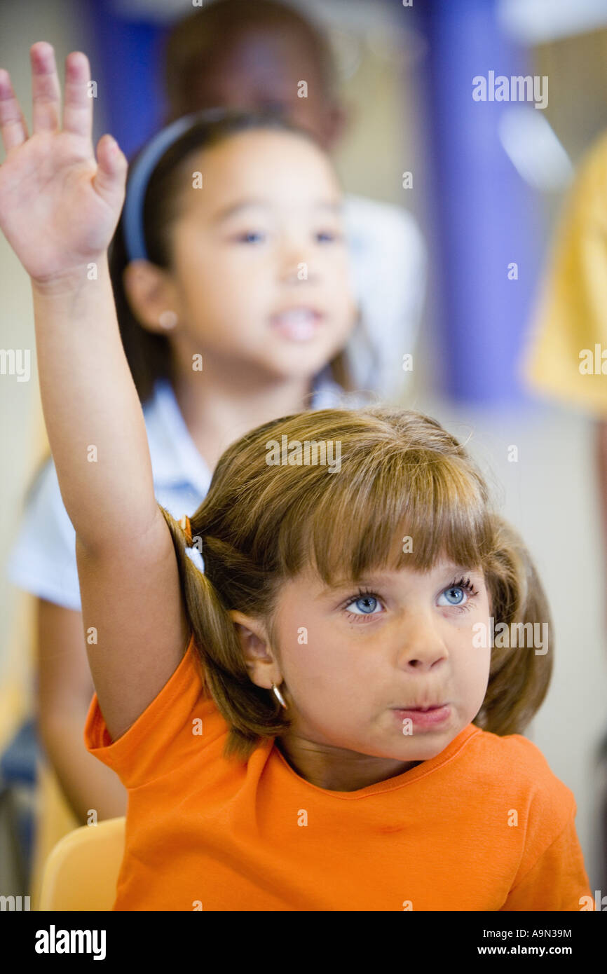 Girl raising hand in a classroom Stock Photo - Alamy