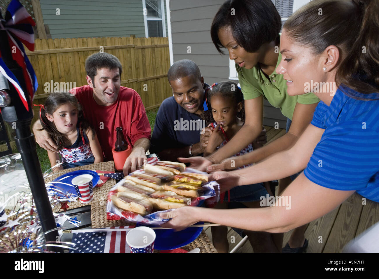 Two families on backyard patio enjoying a cookout on the 4th of July ...