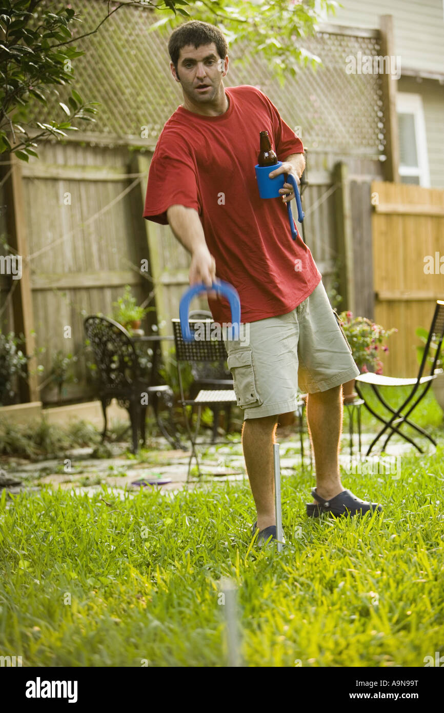 Man tossing horseshoes in backyard Stock Photo - Alamy