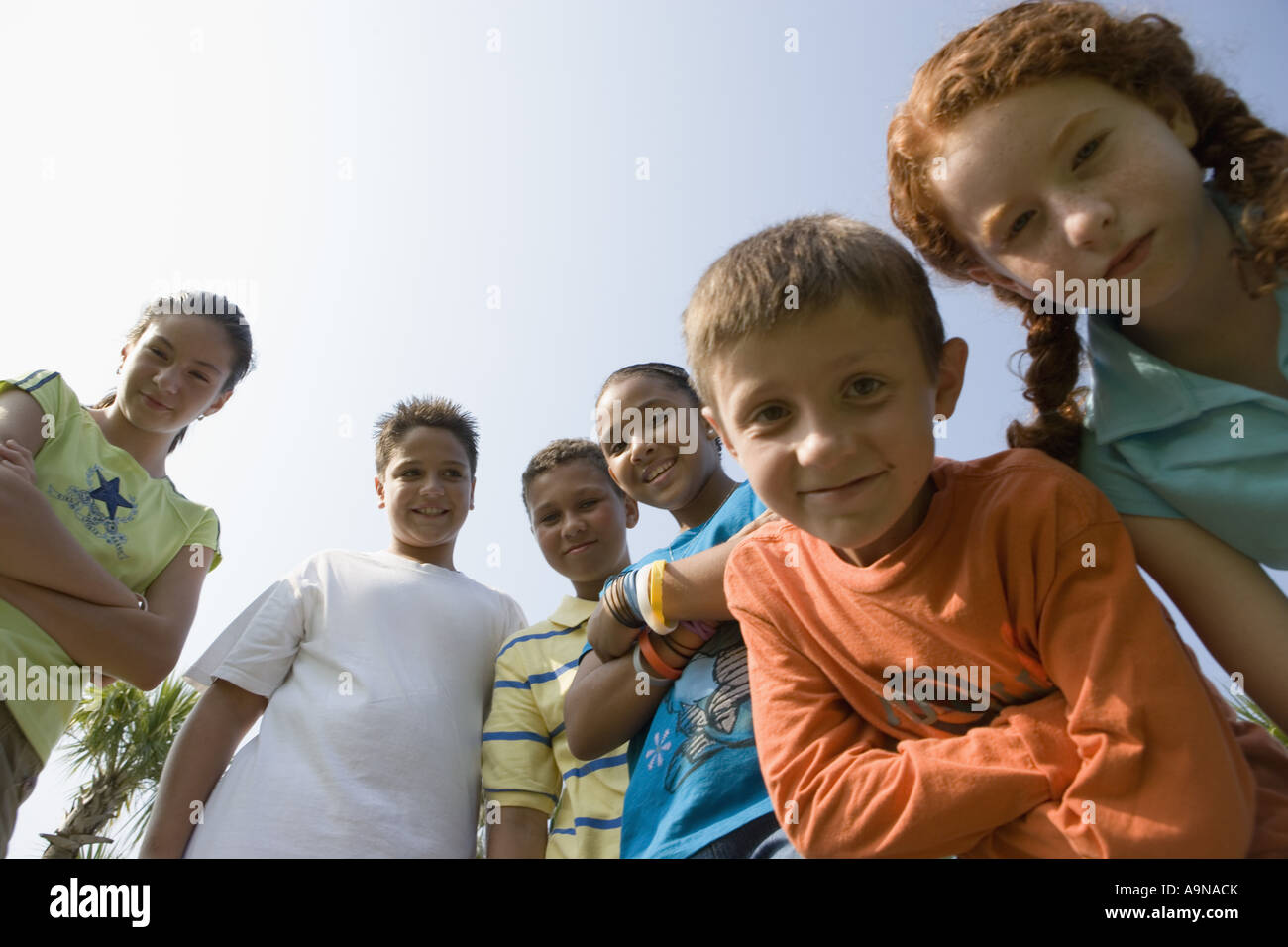Low angle view of children with folded arms standing together at a ...