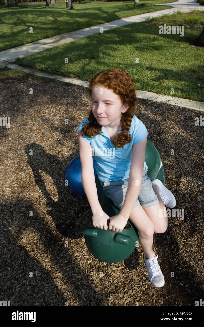 Girl sitting on a rocker at a playground Stock Photo - Alamy