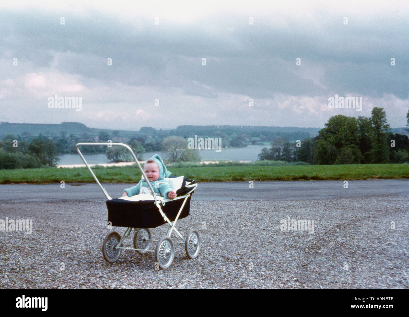 Caucasian baby sitting up in a pram with the British countryside in the ...