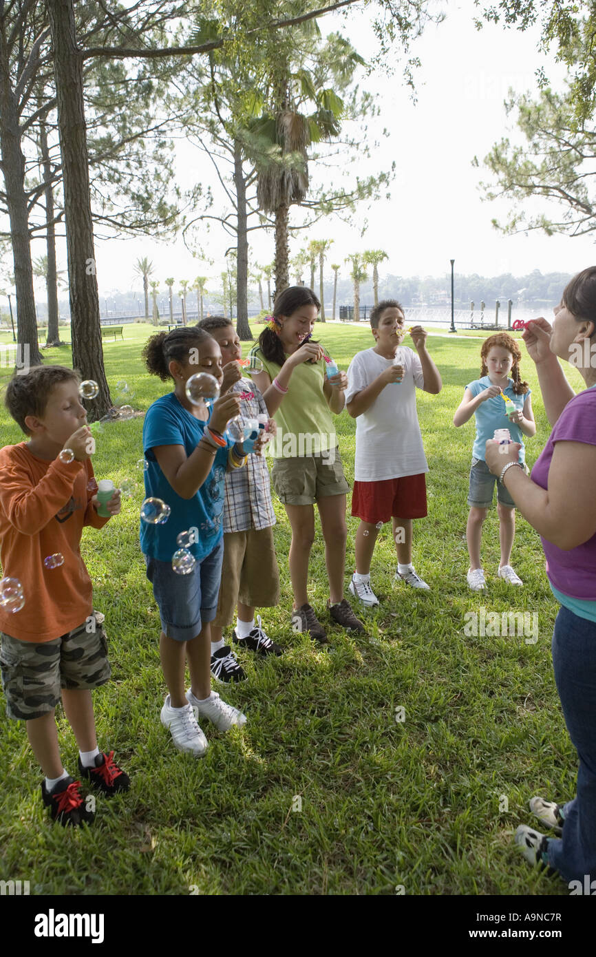 Teacher and children blowing bubbles at a park Stock Photo - Alamy