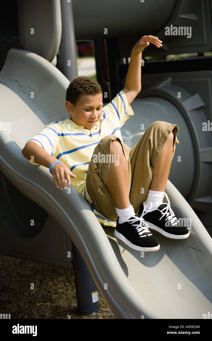 Boy at a playground sliding down a slide Stock Photo - Alamy