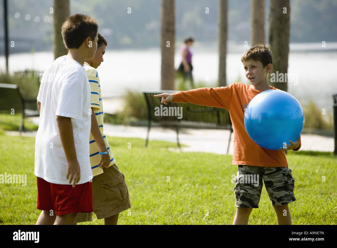Boy with large blue ball playing with and giving instructions his ...