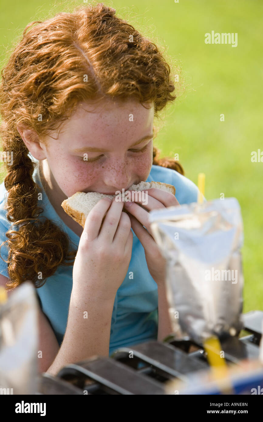 Close-up of girl biting into a sandwich at a picnic table Stock Photo ...