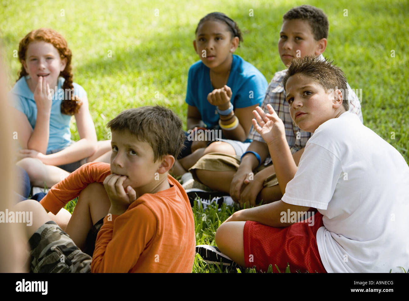 Children sitting in a circle on the grass at a park Stock Photo - Alamy