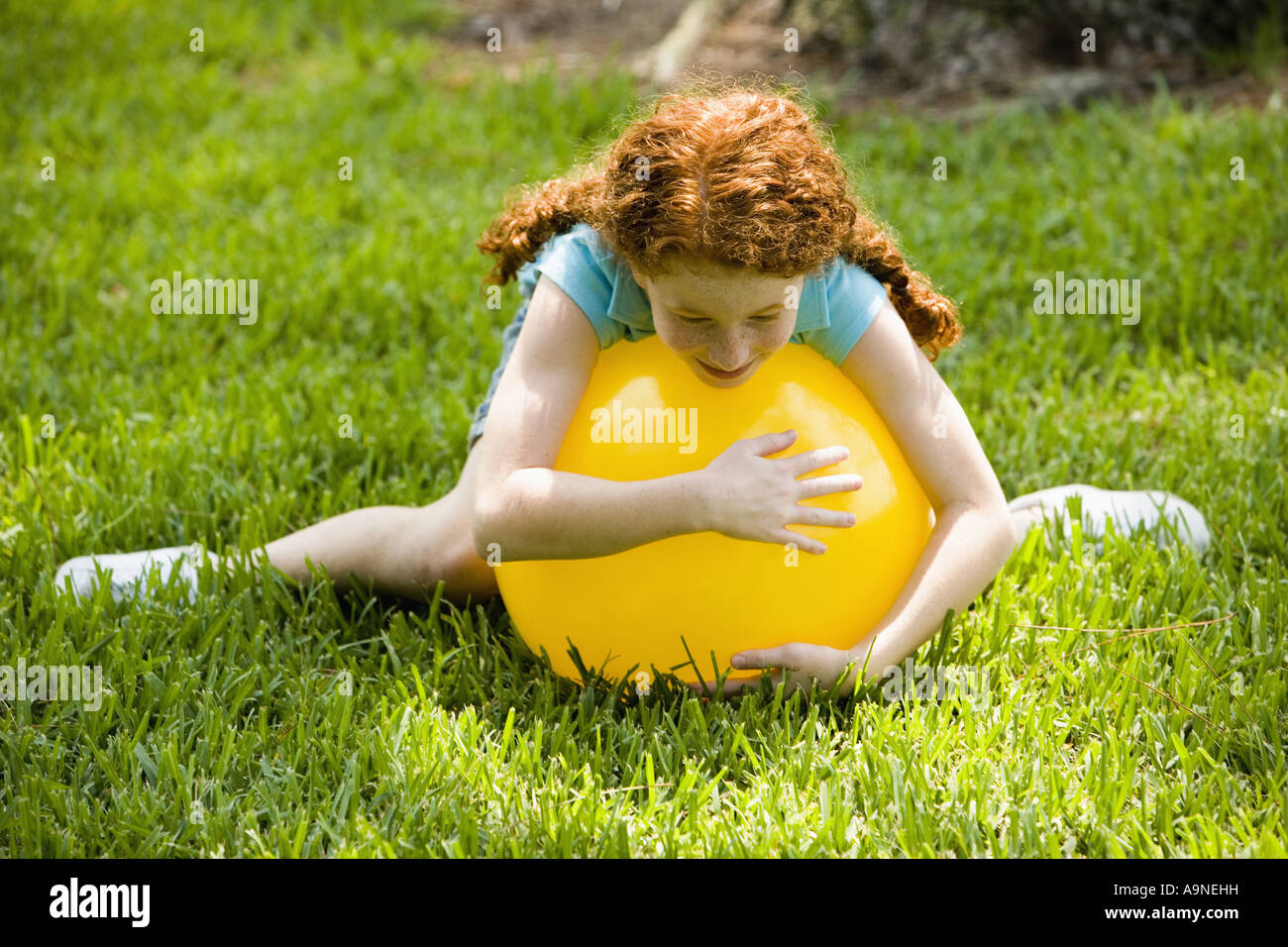 Girl lying on top of a big inflated yellow ball Stock Photo - Alamy