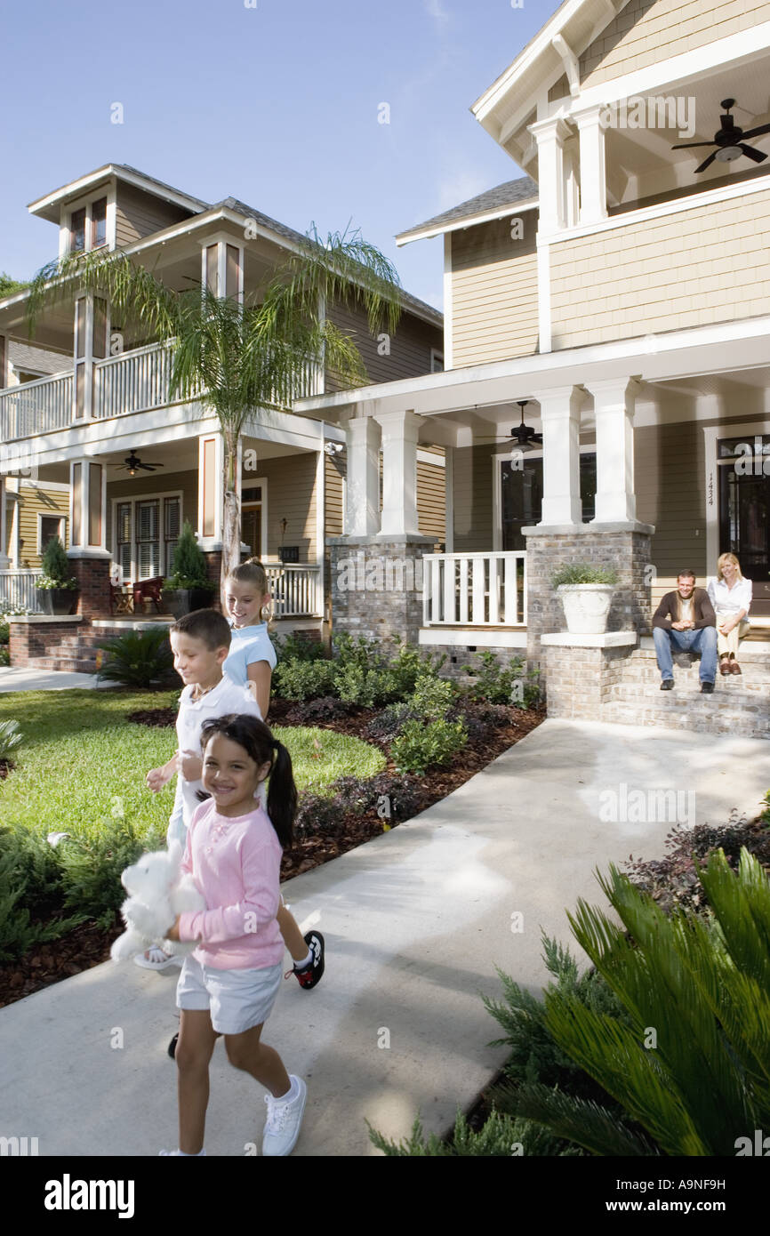 Three children in front of their house while their parents watch from ...
