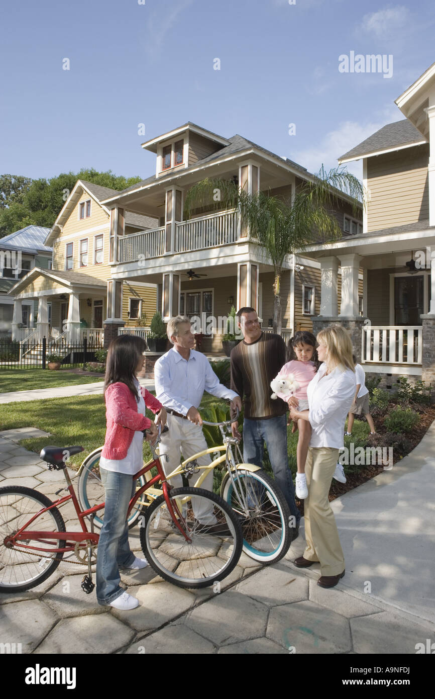 Family with young child conversing with neighbors in front of house ...